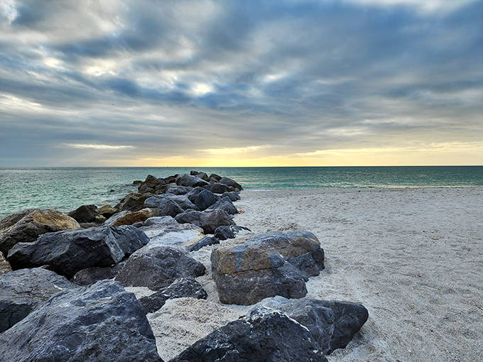 Nature's breakwater: These rugged rocks stand sentinel against Gulf waves, creating peaceful pools where beachcombers hunt for prehistoric treasures.