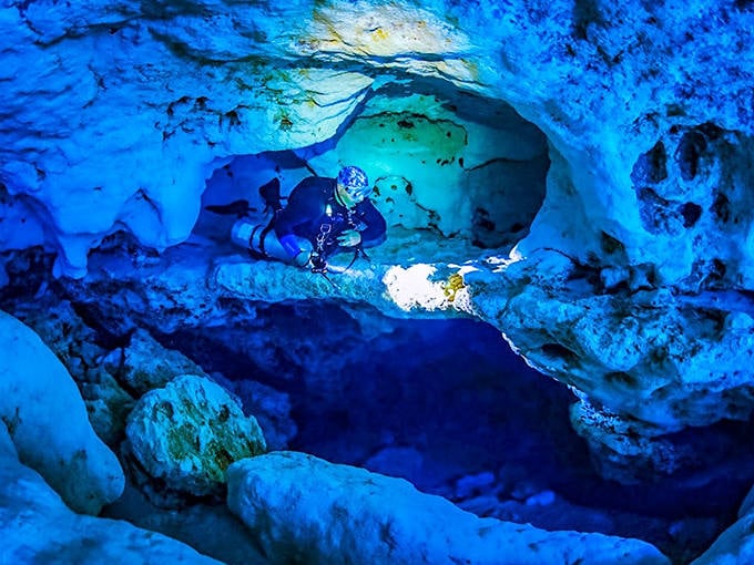 A diver explores Ginnie Springs' underwater caverns, where the surreal blue glow makes it feel like swimming through liquid sky.