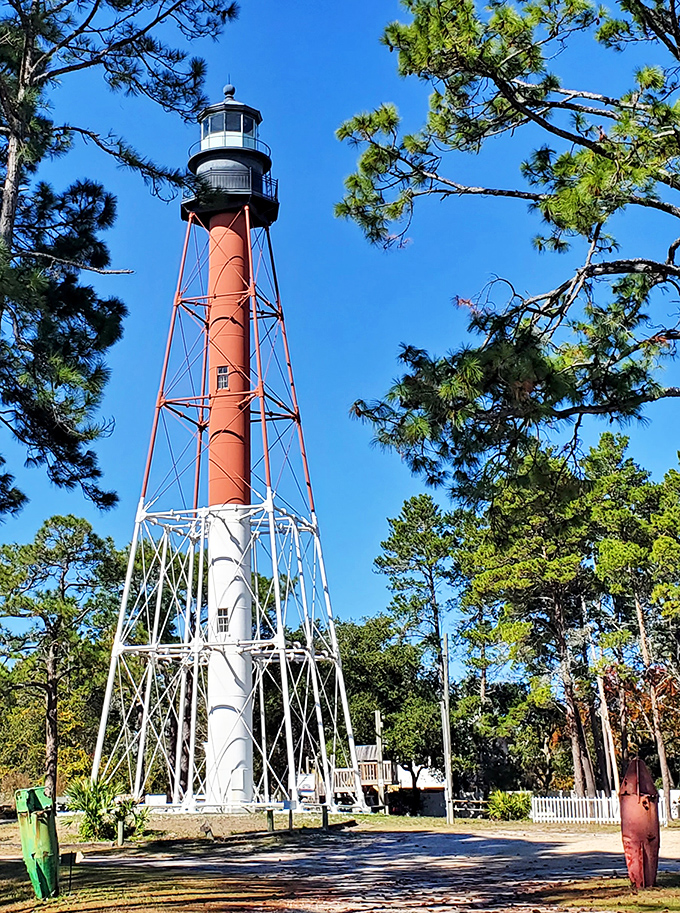 The Crooked River Lighthouse stands tall against azure skies, its red tower a beacon of maritime history since 1895.