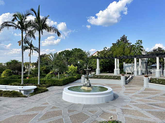Water dances in the sunlight as the central fountain creates a focal point surrounded by geometric pathways and lush greenery.