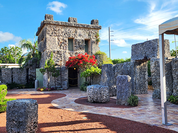 The castle's stone tower stands like a miniature fortress, surrounded by vibrant bougainvillea that adds splashes of color to the coral landscape.