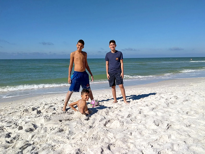 Beach day bliss: Young visitors enjoying the perfect combination of soft sand and gentle Gulf waters at Clam Pass.