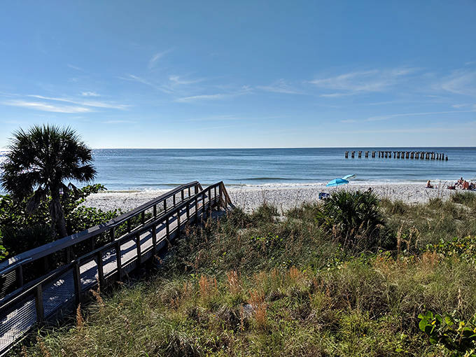 The wooden boardwalk invites visitors to journey from coastal scrub to pristine shoreline, each step bringing you closer to that perfect beach day.