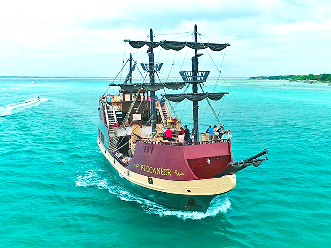 The Buccaneer slices through Destin's famous emerald waters, its three masts standing tall against the perfect blue Florida sky.
