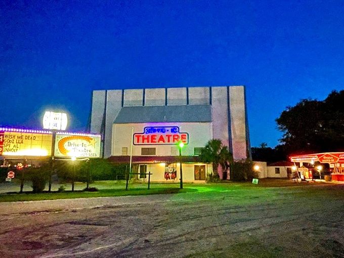 The Ocala Drive-In's towering screen awaits nightfall, when movie magic will transform this simple lot into an outdoor cinema paradise.