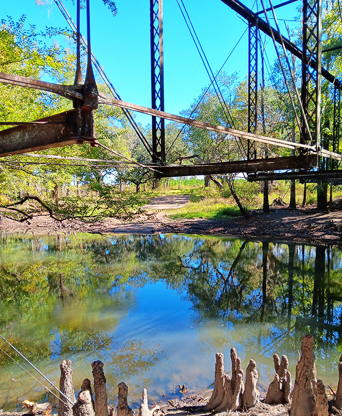 Morning mist creates an ethereal atmosphere as the bridge's silhouette mirrors perfectly in the still river below.