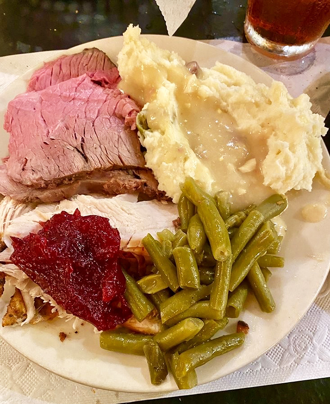A plate of perfectly carved prime rib alongside mashed potatoes, green beans, and cranberry sauce &ndash; comfort food elevated to an art form.
