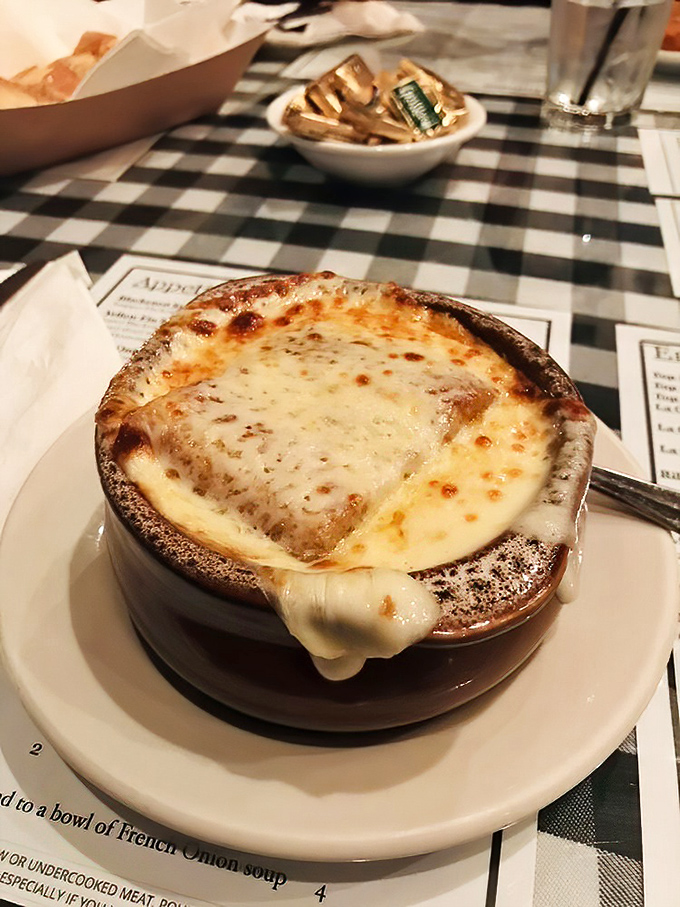 The legendary French onion soup arrives like a cheese volcano, bubbling with promise and decades of perfected flavor.