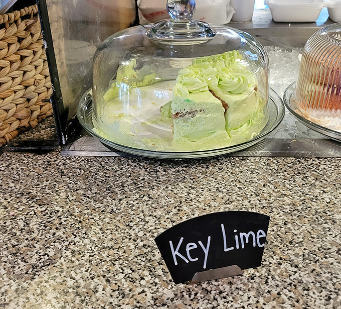 Behold the legendary key lime cake in all its vibrant green glory, sitting proudly under glass like the culinary treasure it truly is.