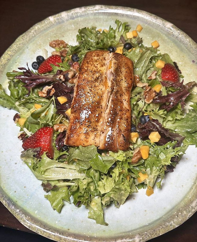 The star of the show! Perfectly blackened mahi-mahi rests atop fresh greens with strawberries, blueberries, and mango chunks creating a flavor explosion.
