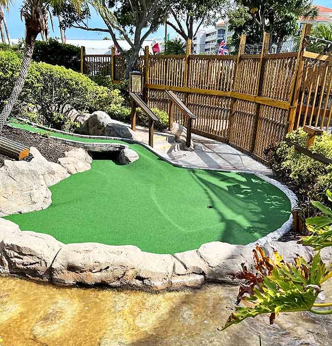 The vibrant green putting surface winds between natural stone formations, creating challenging angles that will test even the most seasoned mini-golfer's skills.