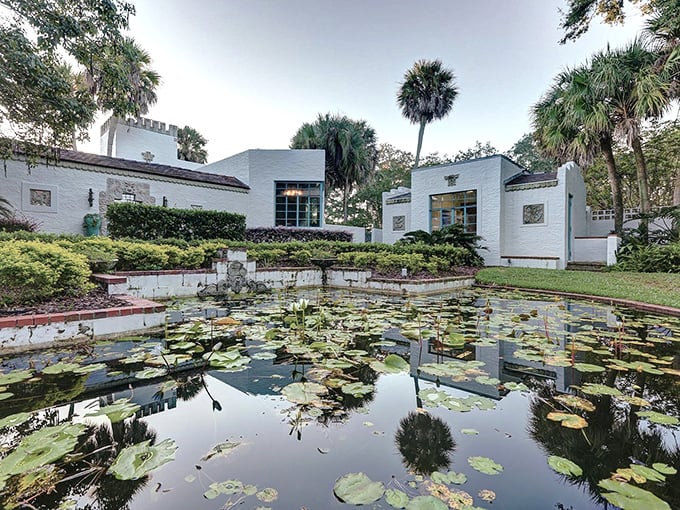 Lily pads float like green constellations on this tranquil reflection pond, mirroring the white buildings and swaying palms in perfect symmetry.