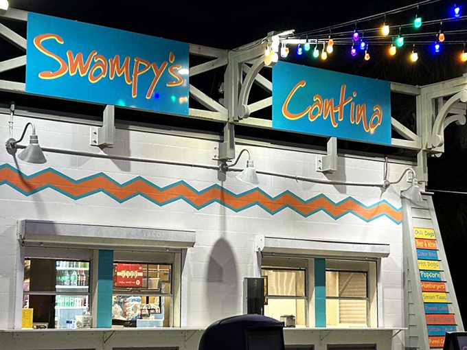 Swampy's Cantina lights up the night with colorful signage and festive string lights, offering hungry adventurers a tropical-themed refueling station.