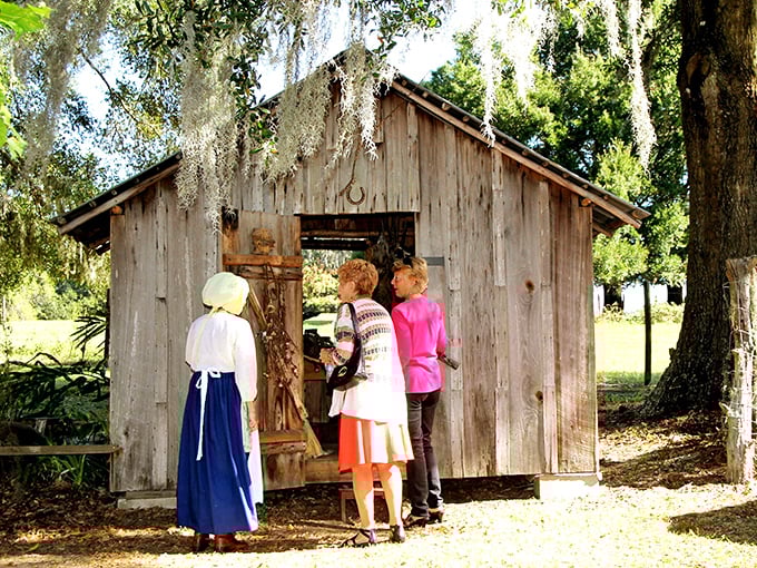 Living history in action: Visitors engage with costumed interpreters outside a rustic cabin, where Florida's pioneer stories come alive through personal interaction.