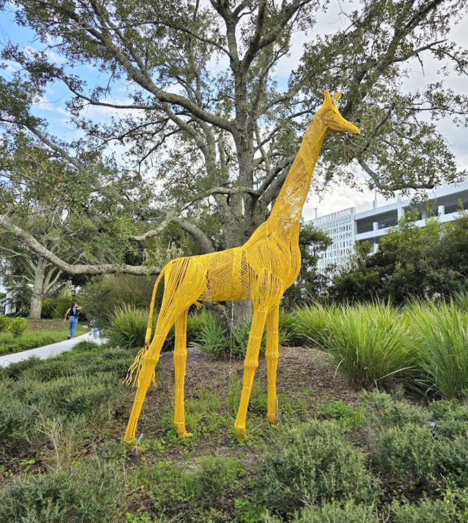 Like a sunshine-dipped sketch come to life, this yellow wire giraffe stretches skyward among ancient oaks.