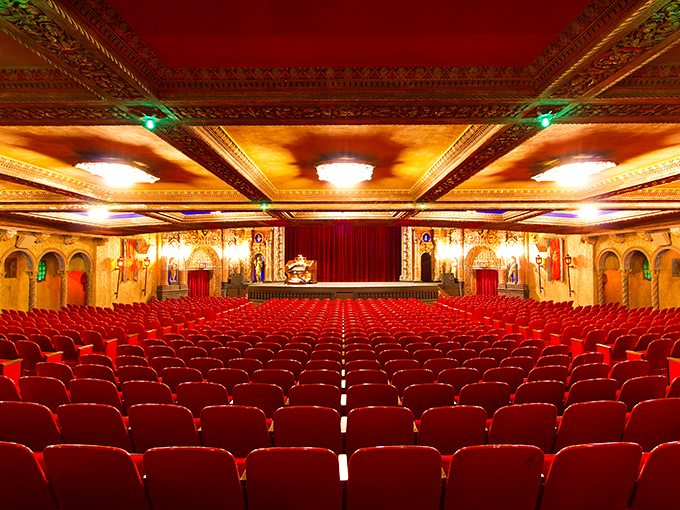 Red velvet seats face a stage framed by architectural extravagance, proving that sometimes the theater itself deserves as much attention as what's on screen.