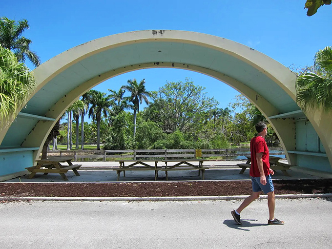 A solitary visitor walks beneath the massive concrete arch, perhaps contemplating how this space has transformed from zoo attraction to accidental architectural wonder.