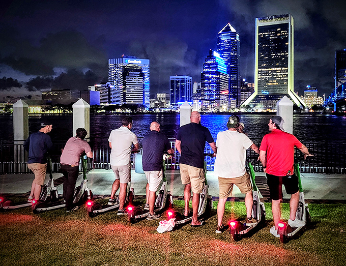 Night adventurers on electric scooters pause to take in Jacksonville's illuminated skyline &ndash; proof that the best city tours happen after dark.