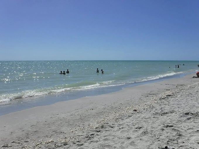 Gentle waves kiss the shoreline at Bowman's Beach, where beachgoers enjoy the simple pleasure of wading in crystal-clear Gulf waters.