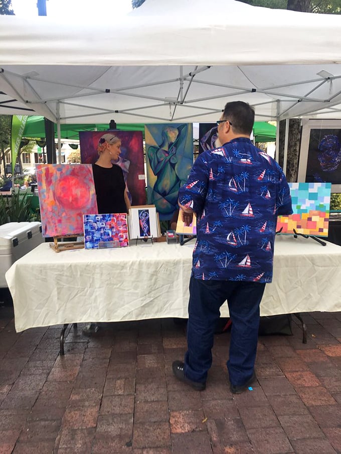 Local artists display their colorful creations under white tents, turning the park into an open-air gallery where art meets everyday life.