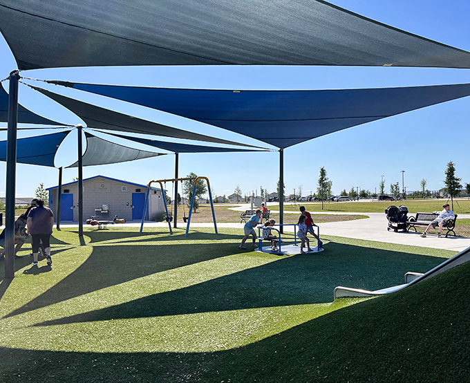 Modern playground equipment under protective shade sails where children's laughter provides the perfect soundtrack to a sunny afternoon.