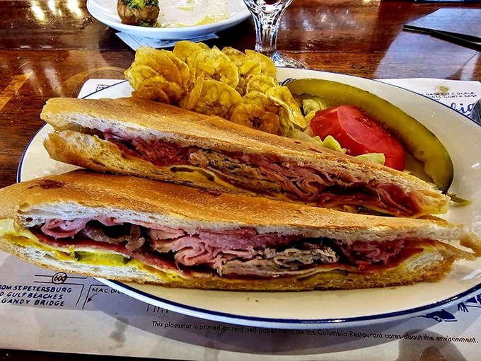 Layer upon layer of ham, roast pork, Swiss cheese, pickles, and mustard create the perfect harmony in this pressed masterpiece, served with golden plantain chips.