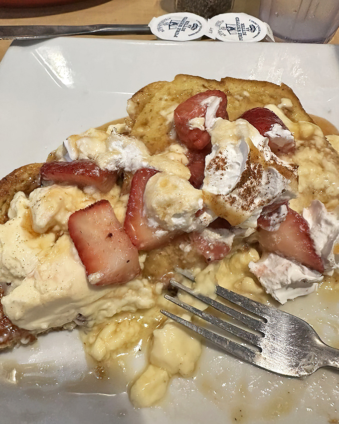 French toast elevated to art form – golden bread islands floating in a sea of strawberries and cream, waiting for that maple syrup waterfall.