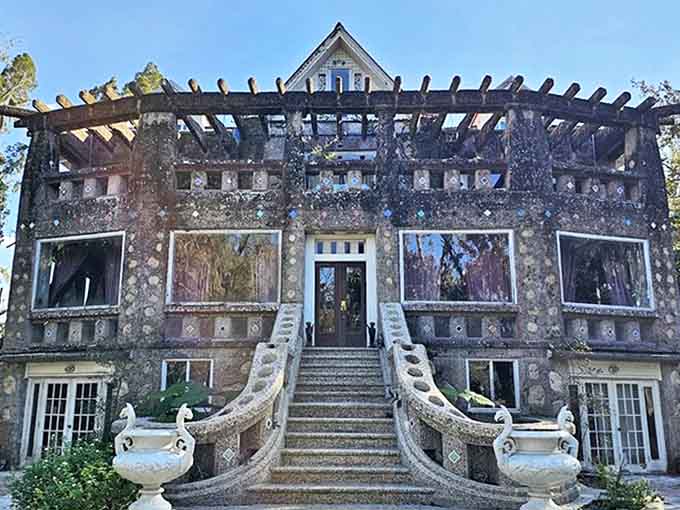 Grand staircases curve upward to the entrance, flanked by decorative urns that stand like sentinels guarding the secrets of this peculiar Florida landmark.