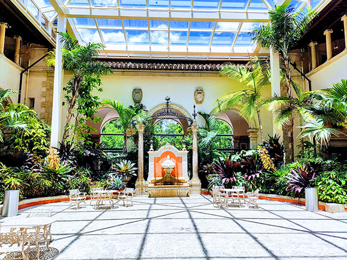 An indoor courtyard where tropical plants thrive under glass, because why choose between inside and outside when you can have both?