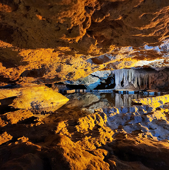 Reflective pools mirror golden cavern ceilings, creating a double vision of geological masterpieces sculpted by time and water. cave