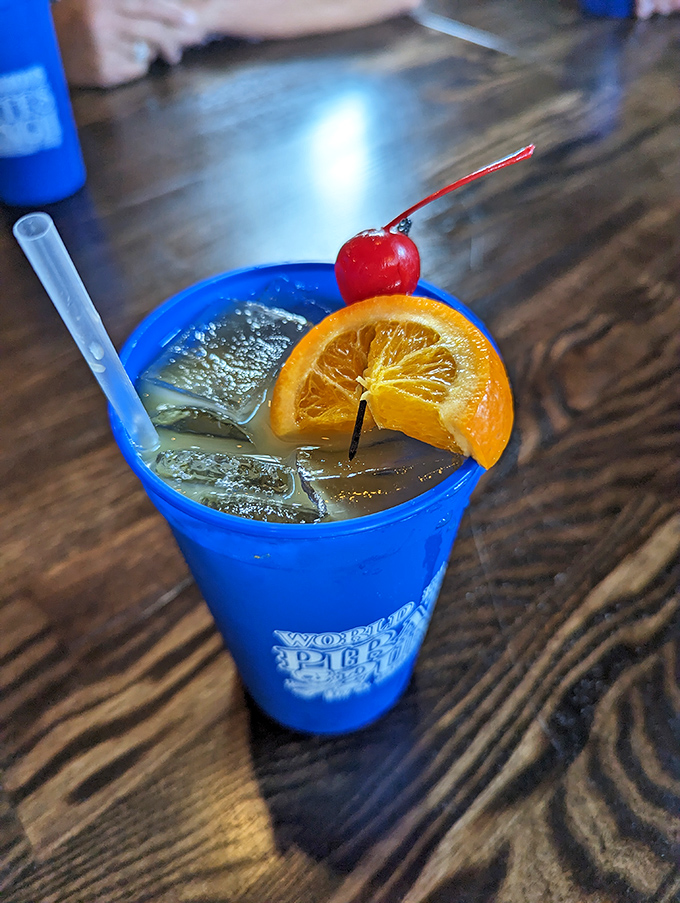 The vibrant blue punch arrives like liquid vacation in a glass, its orange slice and cherry adding a pop of color against the electric azure.