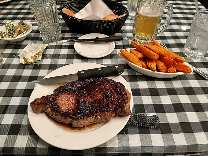 A masterpiece of marbling rests beside golden sweet potato fries &ndash; the steak's charred exterior giving way to a perfectly pink center.