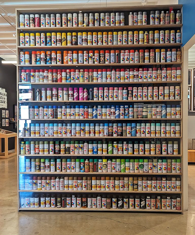 Spray Paint Can Color Archive Wall: The artist's arsenal displayed with museum precision &ndash; hundreds of paint cans arranged like a hardware store designed by Warhol himself.