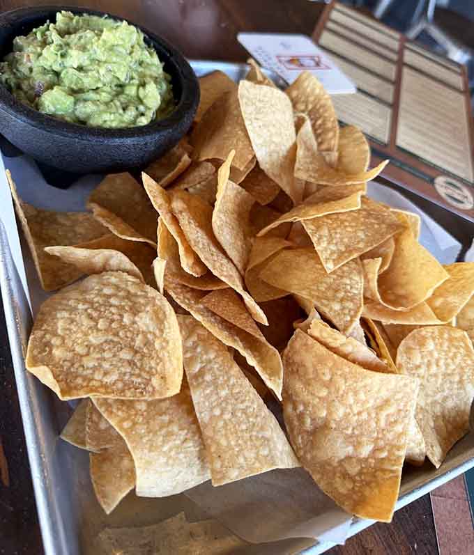 Fresh tortilla chips and guacamole so green it practically glows, because apparently even the appetizers here refuse to be ordinary.