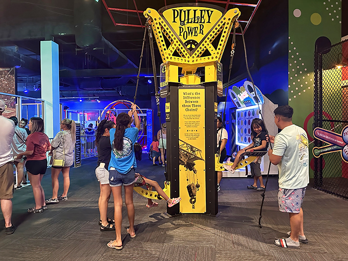 Families test their skills at the "Pulley Power" station, discovering physics principles through hands-on play rather than textbook diagrams.
