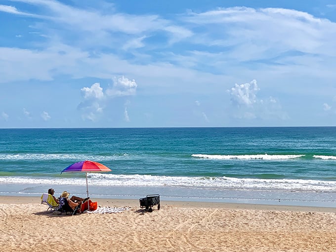 A perfect Florida moment captured: endless blue horizon, gentle waves, and someone who clearly understands the art of proper beach lounging.