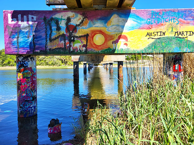 Viewed from below, the bridge's painted pillars rise from the water like technicolor monuments to creative freedom.
