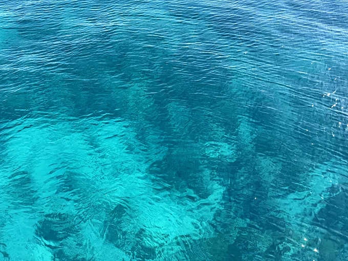 Blue blurs frame the deceptively ordinary surface waters, beneath which lies an extraordinary underwater metropolis of memories.