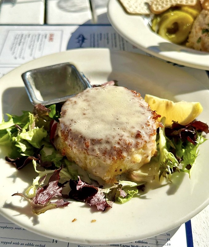 Famous crab cakes: Golden-brown perfection on a bed of greens &ndash; minimal filler, maximum flavor, and a sauce worth bottling and taking home.
