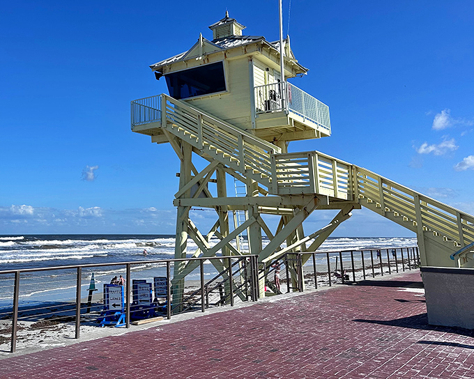 The iconic lifeguard stand watches over swimmers and sunbathers, a cheerful sentinel against the backdrop of rolling waves.