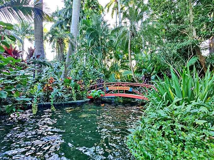 A colorful footbridge arches gracefully over still waters, connecting garden paths while reflecting in the pond below.
