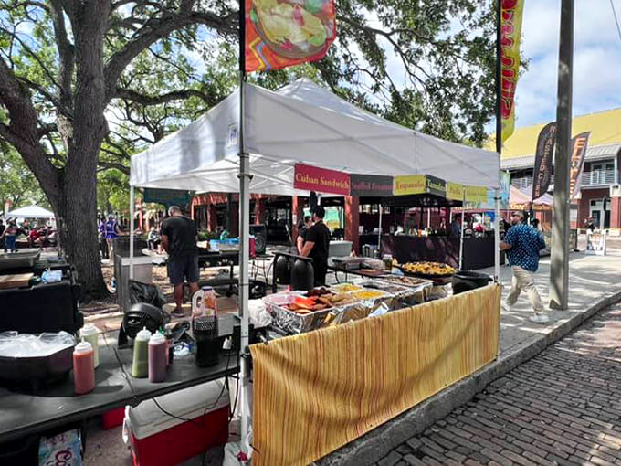 Festival booths showcase Cuban sandwiches and international flavors under shady tents where hungry crowds gather for authentic street food experiences.