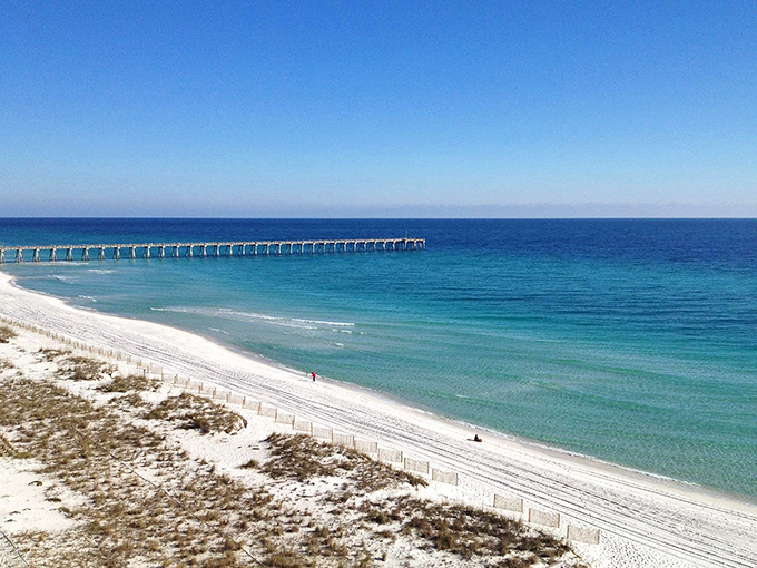 Wow, look at that water! The dazzling emerald coastline and long fishing pier are simply breathtaking under this blue sky.