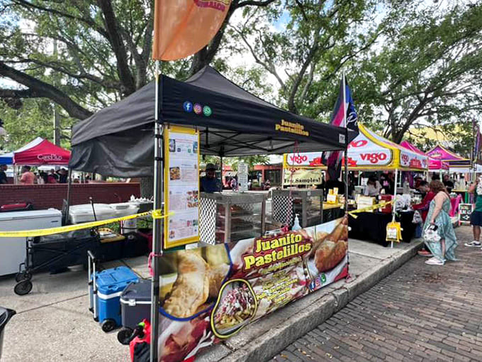 Pastelitos and empanadas tempt passersby at Juan's booth, proving that the best festival foods come in perfectly portable packages.