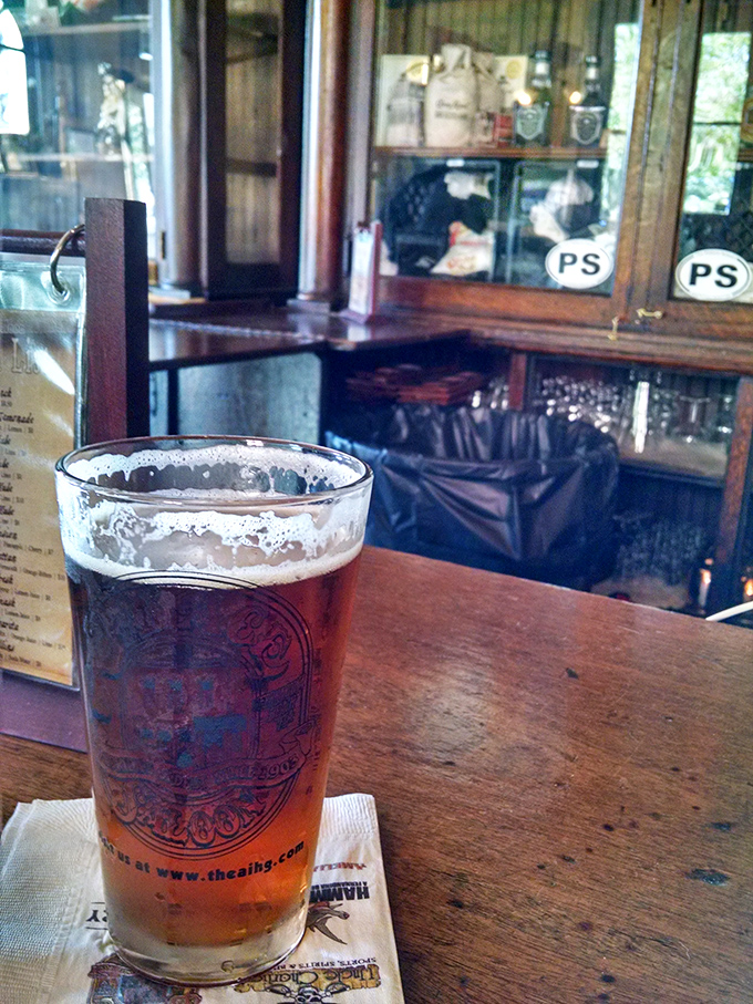 A perfectly poured amber brew sits atop the worn wooden bar, the glass catching light that's illuminated countless toasts since the early 1900s.