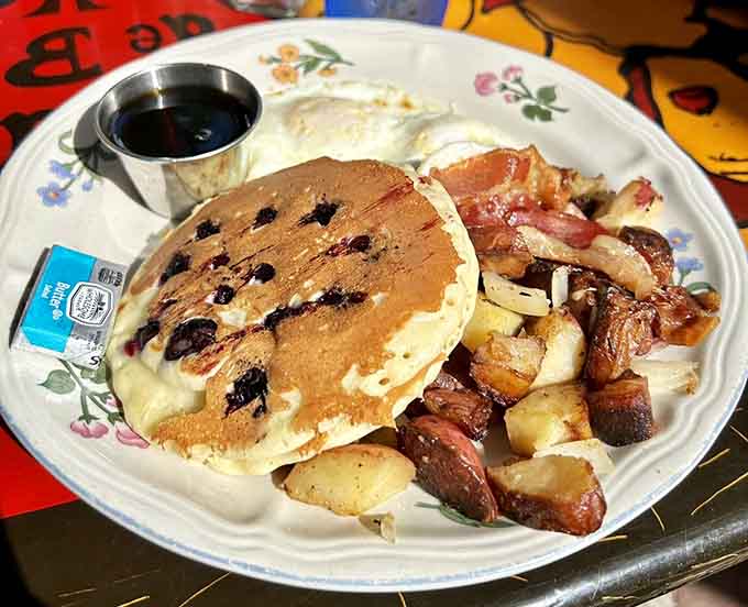Blueberry pancakes stacked high enough to require architectural planning and possibly a building permit.