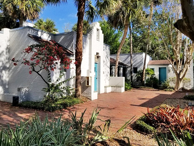 Brick pathways lead through this sun-dappled courtyard, where vibrant bougainvillea provides a splash of color against pristine white walls.
