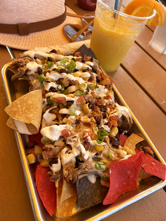 These loaded pork mojo tacos arrive like a fiesta on a plate, topped with creamy sauce and green onions alongside a refreshing tropical drink.