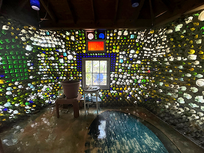 A close-up reveals the intricate arrangement of bottles in the wall, where each glass end creates a porthole of color that transforms ordinary concrete into art.