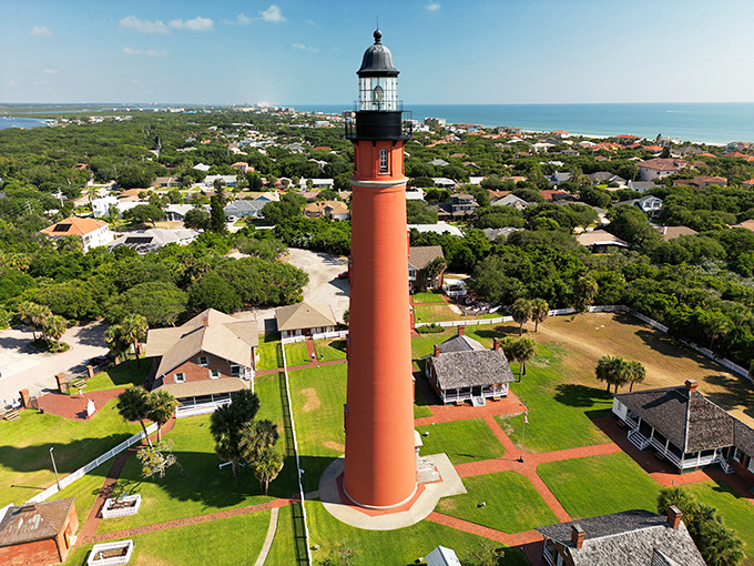 The lighthouse's distinctive silhouette creates a striking contrast against the lush Florida landscape and azure waters beyond.